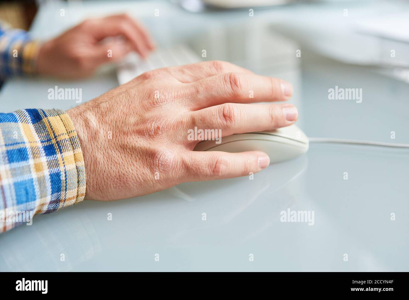 Hand of a senior operating computer mouse and keyboard on the computer ...