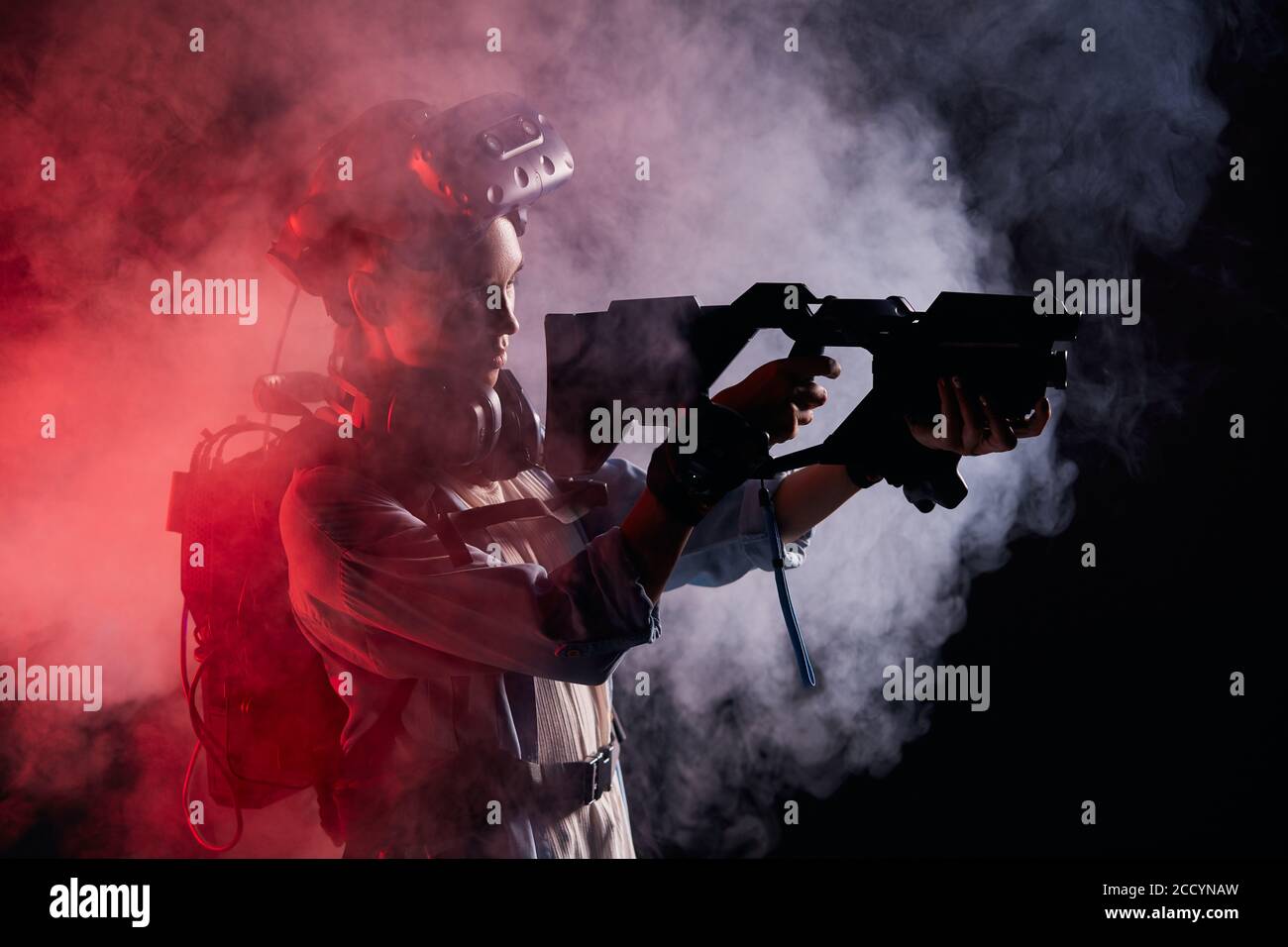 Side view on young woman directing her barrel of virtual gun at side ...