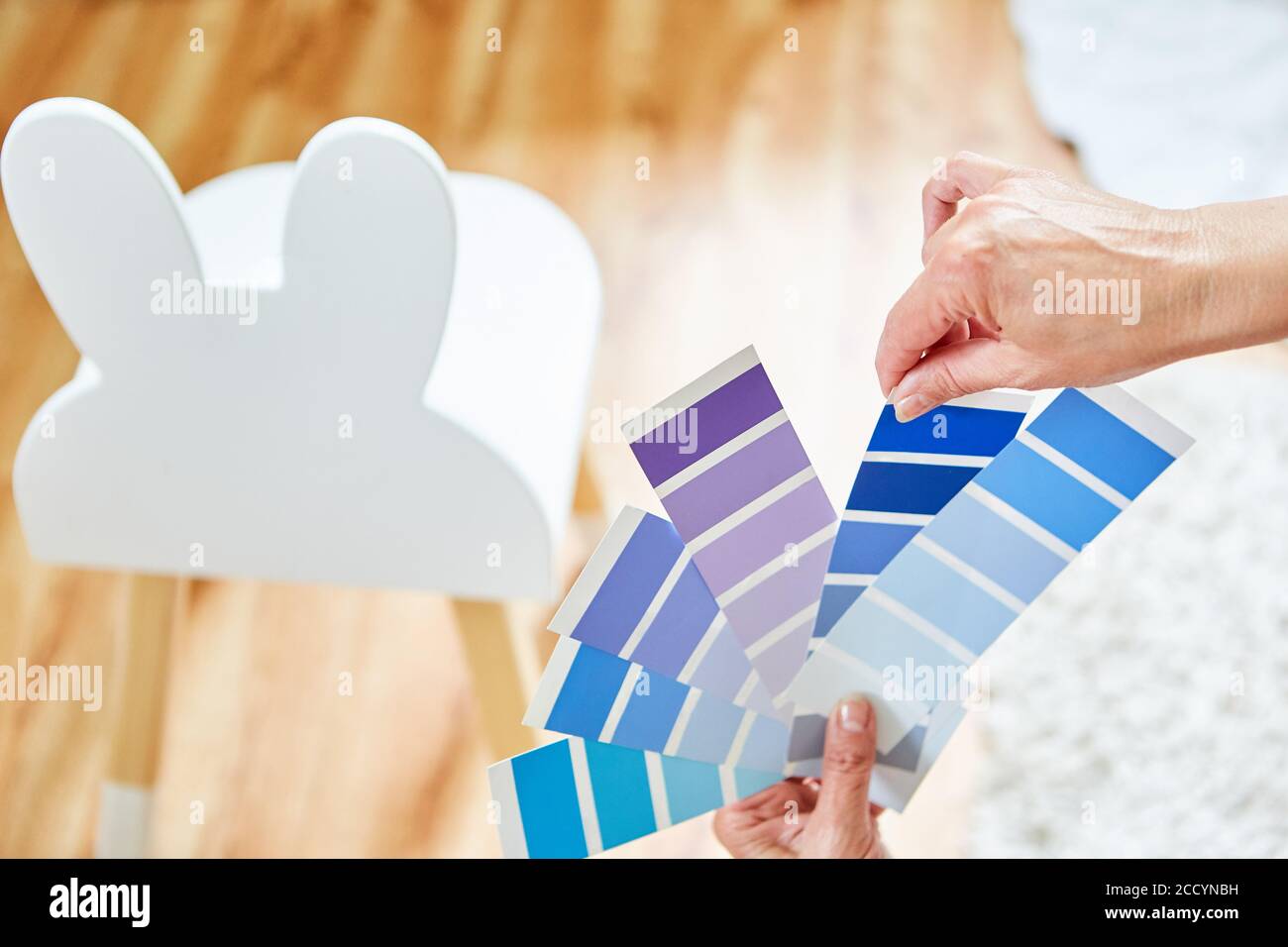 Hand with color fan for color selection when painting a chair during a ...