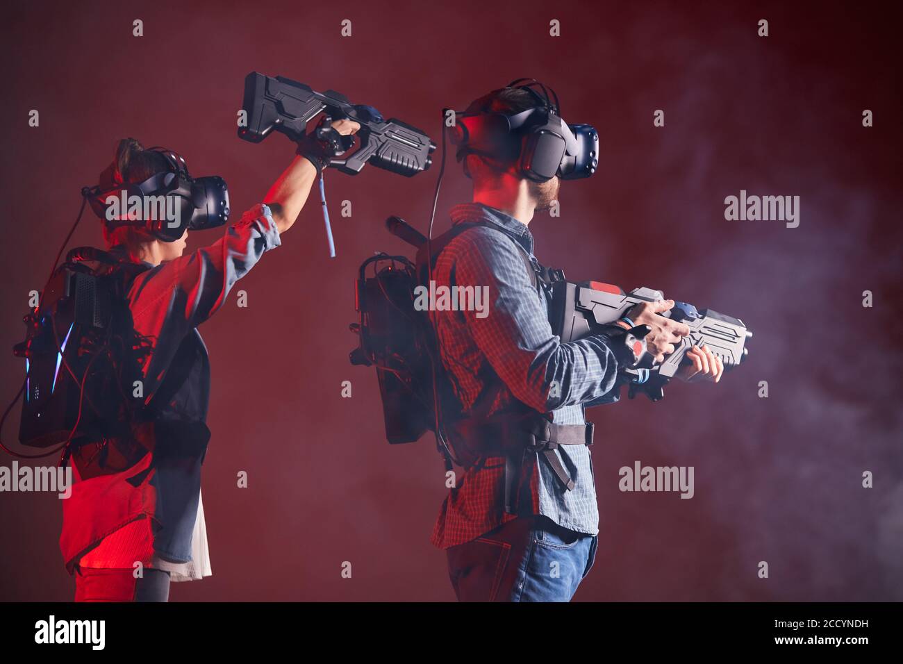 Caucasian man and woman stand holding virtual weapon and wearing goggles, innovation future ...