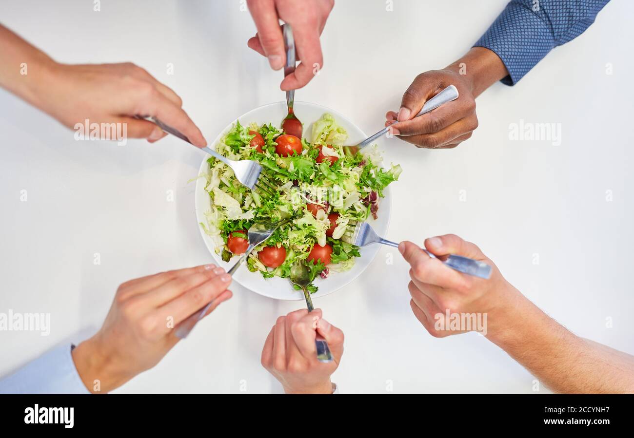Hands with forks of a group of business people eating salad together ...