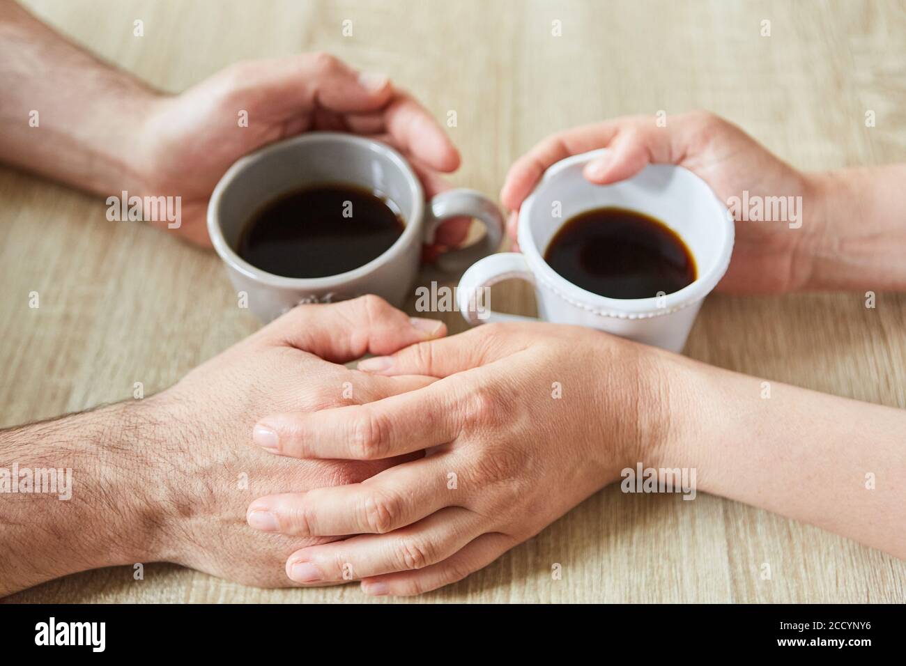 Two hands touch while drinking coffee as a sign of comfort and ...