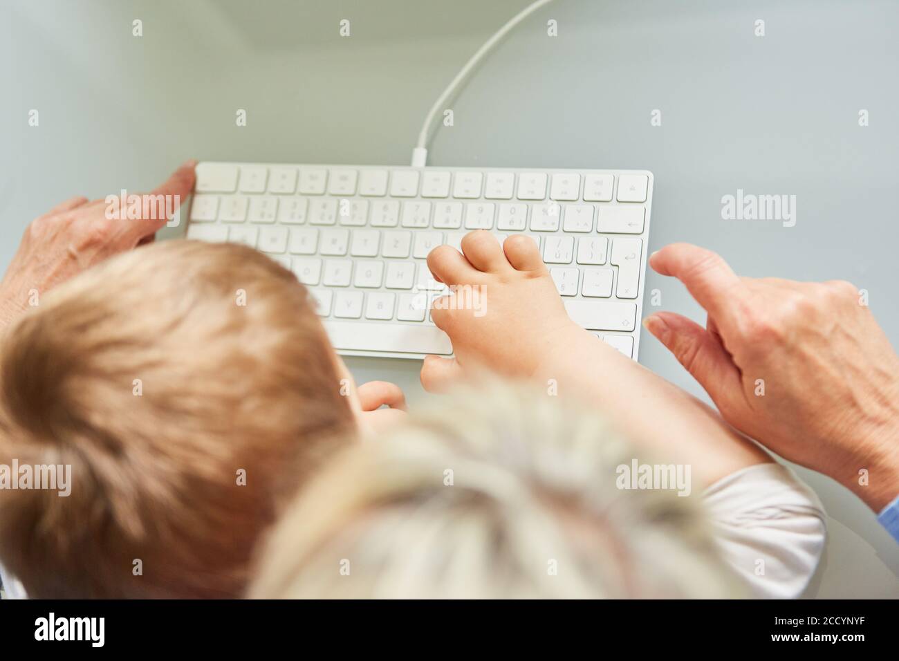 Adult helps child learn to write on the keyboard at the computer Stock ...