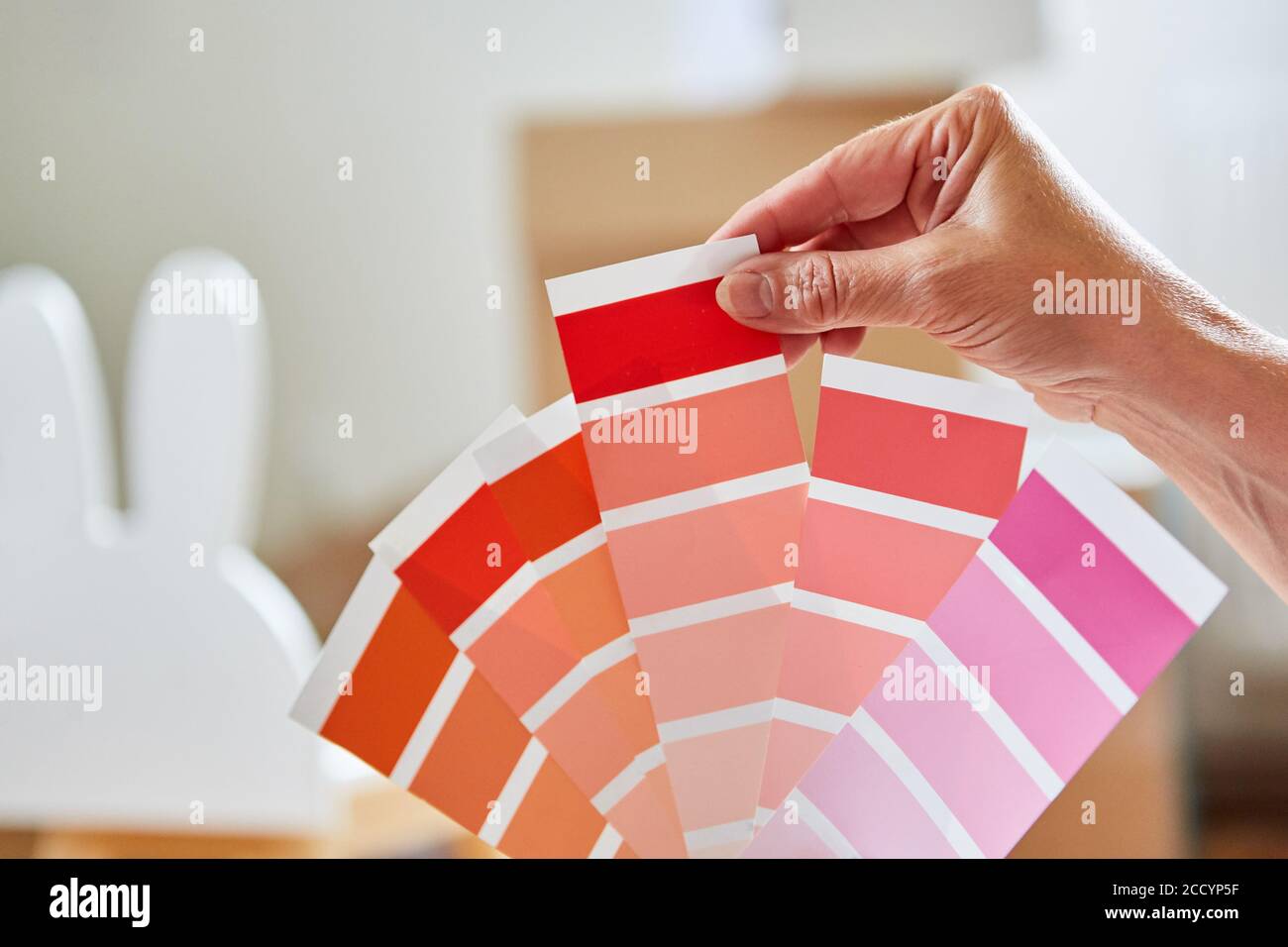 Hand holding color fan while choosing the color to paint the chair as ...