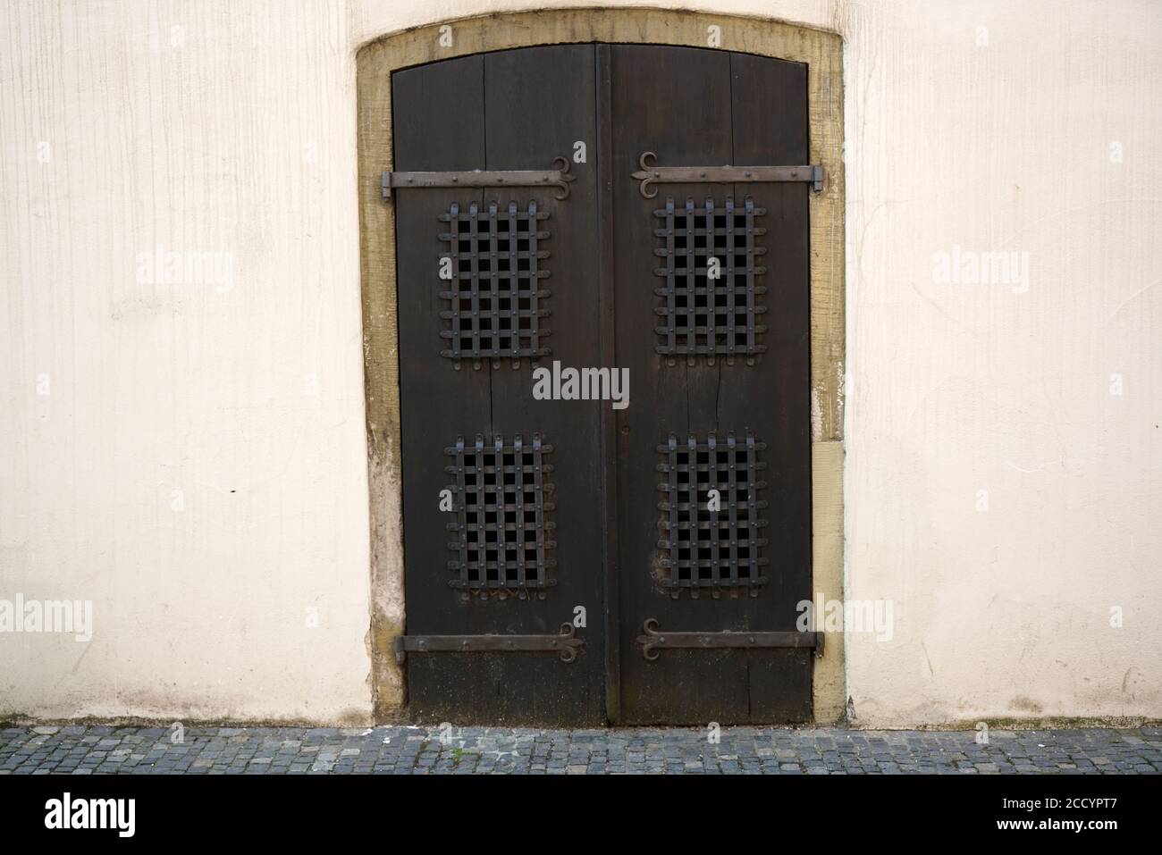 Old wooden door with small metal bar windows Stock Photo - Alamy