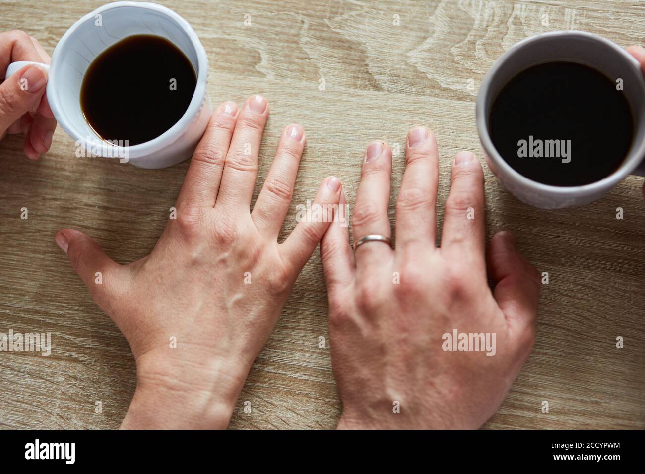 Two hands tenderly touch while drinking coffee as a symbol of love ...