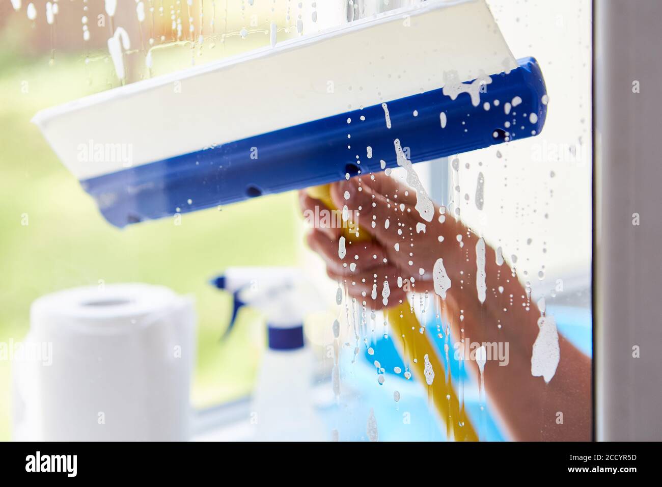 A window cleaner cleans a window with a wiper and soapy water as a ...