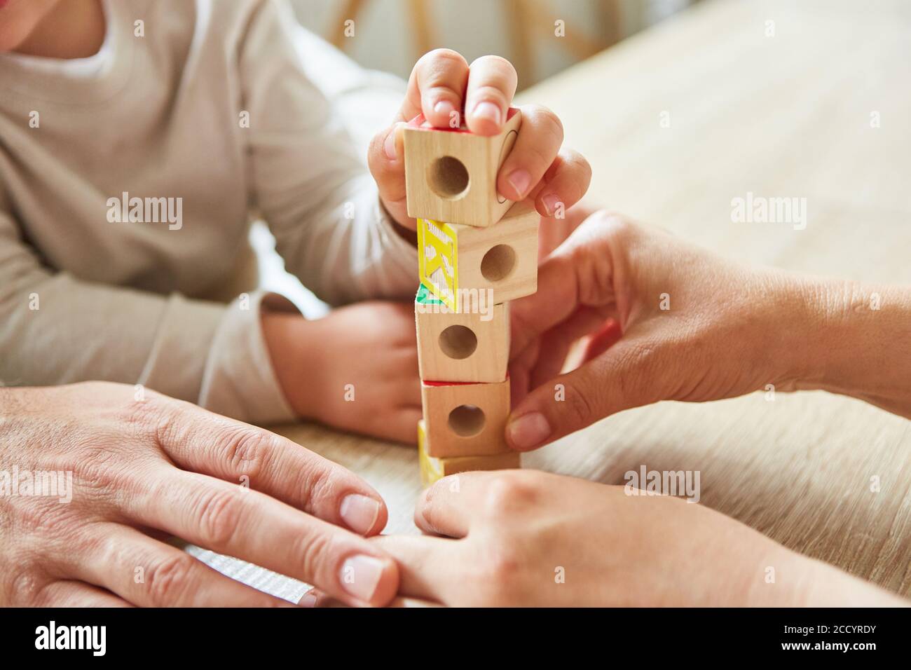 Hands of the elderly and child stack building blocks together as a game ...