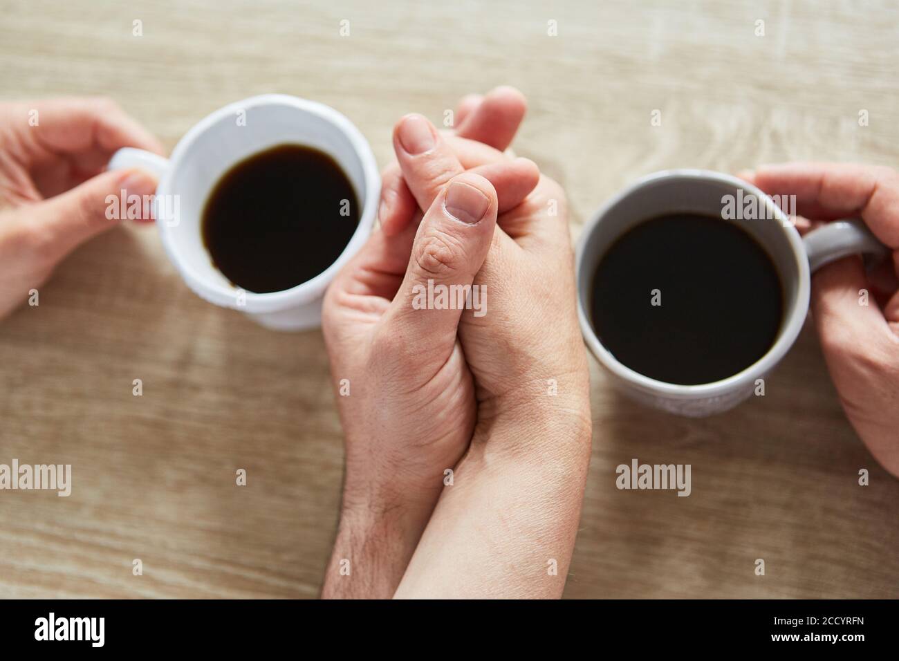 Two hands are touching while drinking coffee as a concept of comfort ...