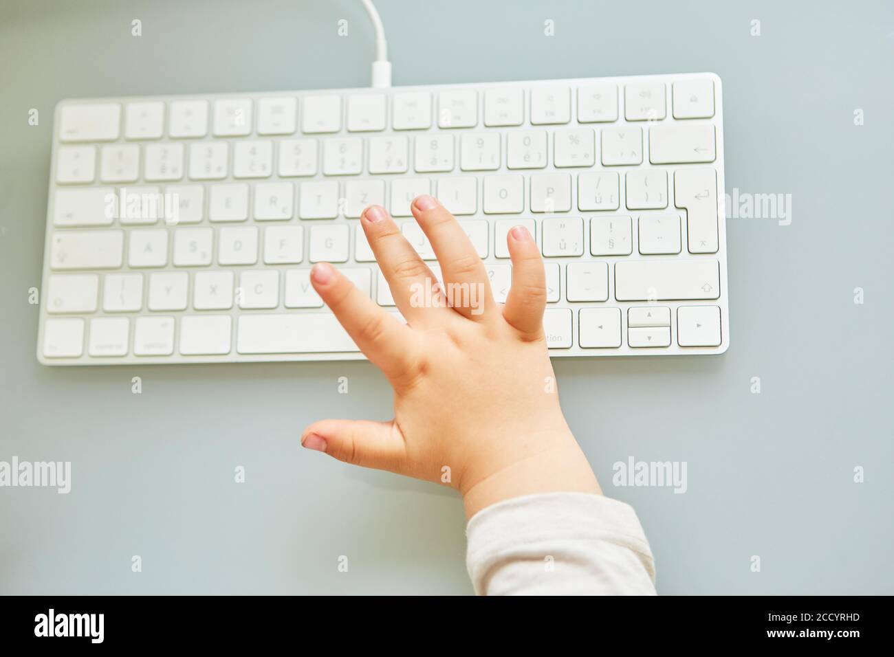 Hand of baby is typing on computer keyboard on a desk Stock Photo - Alamy