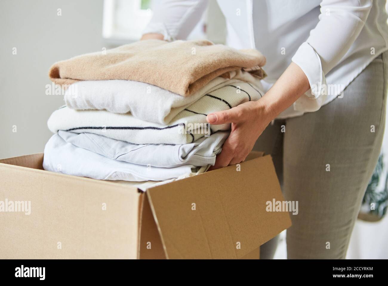 Woman packs clothes in moving boxes for moving or donating clothes ...