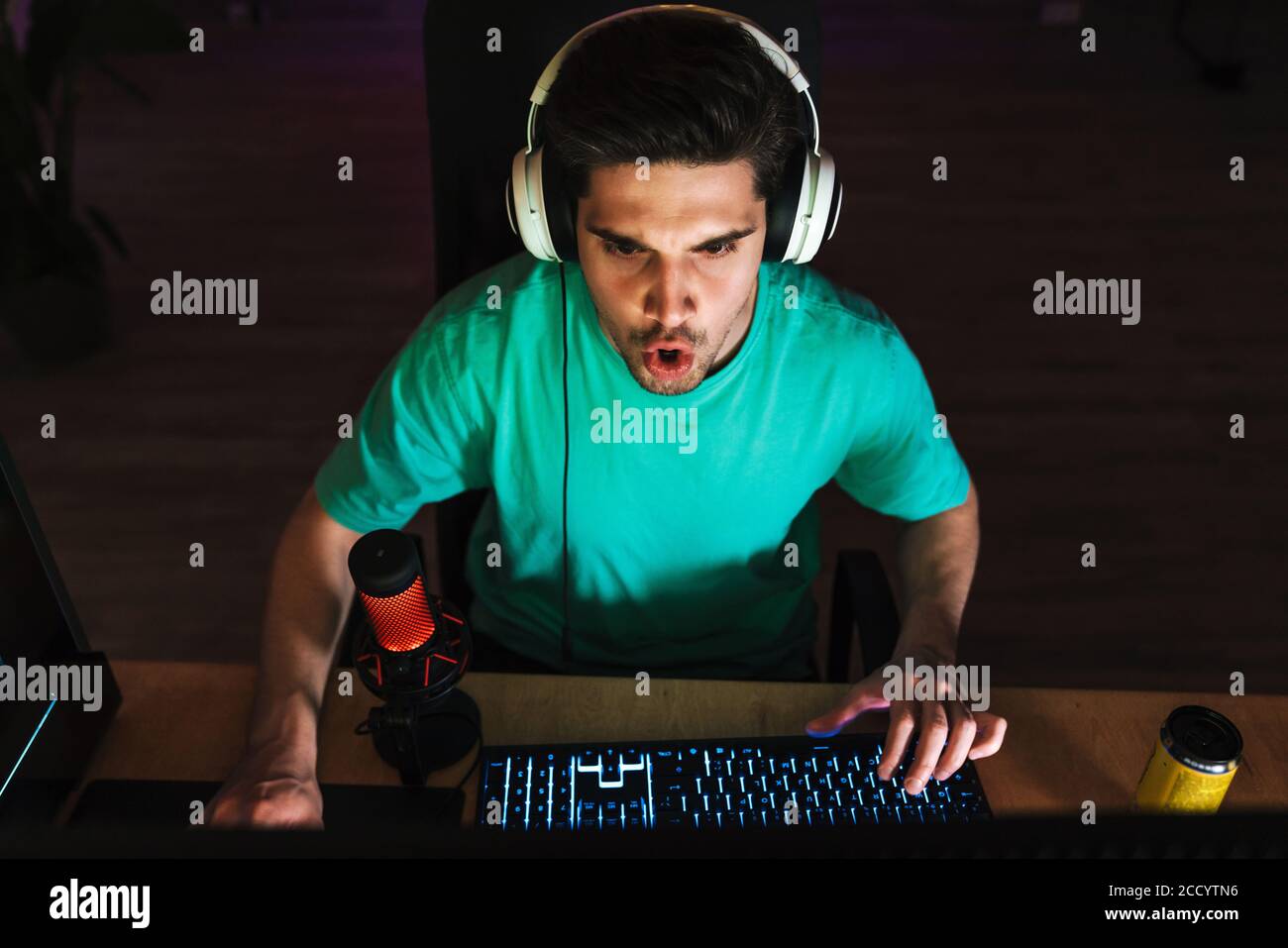 Image of concentrated happy man in headphones playing video game on ...