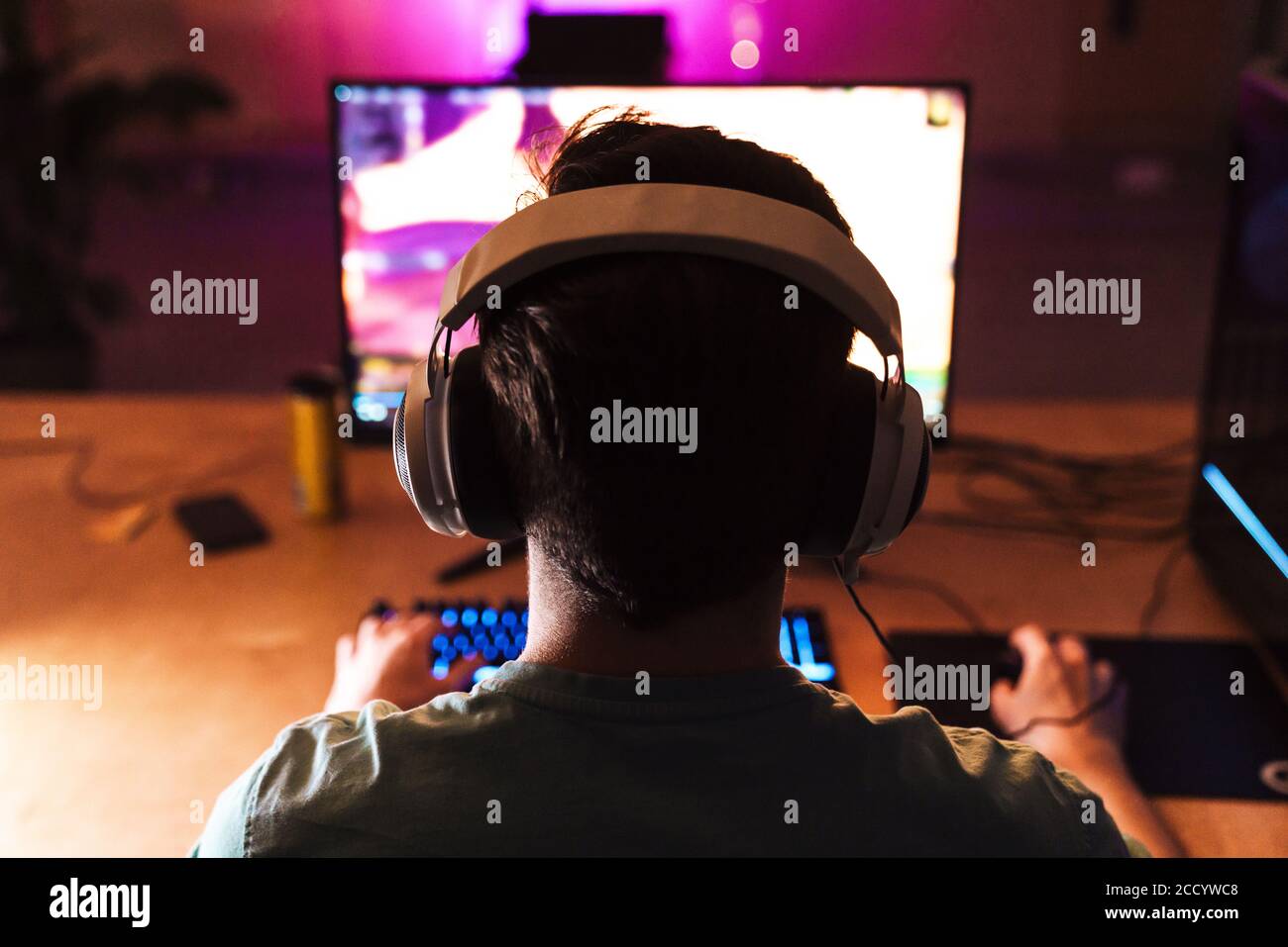 Image of focused man in headphones playing video game on computer while ...