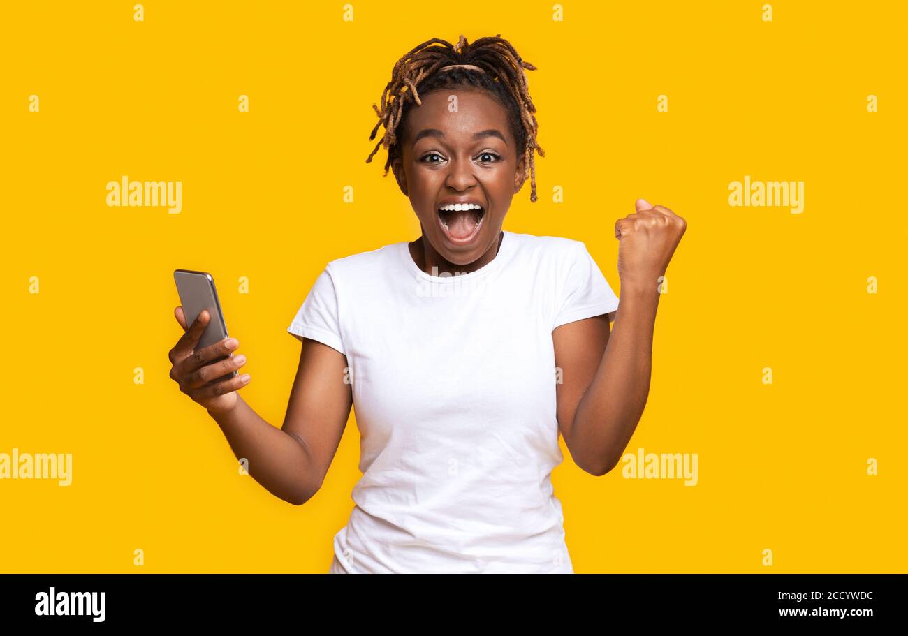 Lucky african woman won lottery, holding mobile phone Stock Photo - Alamy