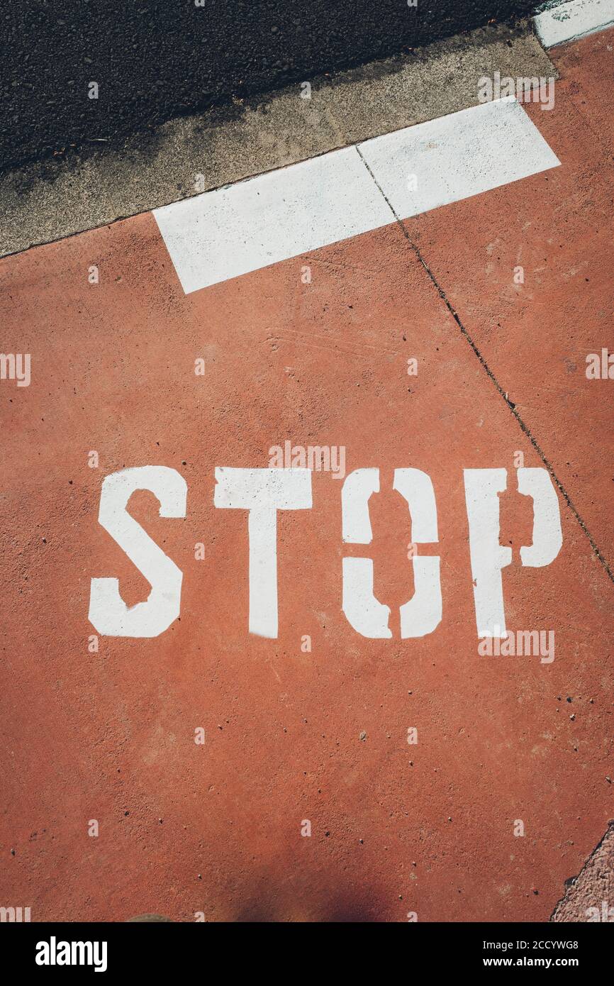 The word stop painted in white capital letters on a red floor Stock ...