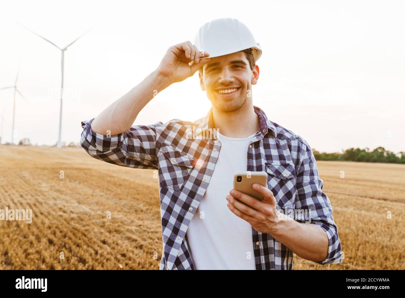 Smiling male engineer using mobile phone while standing at the electric ...