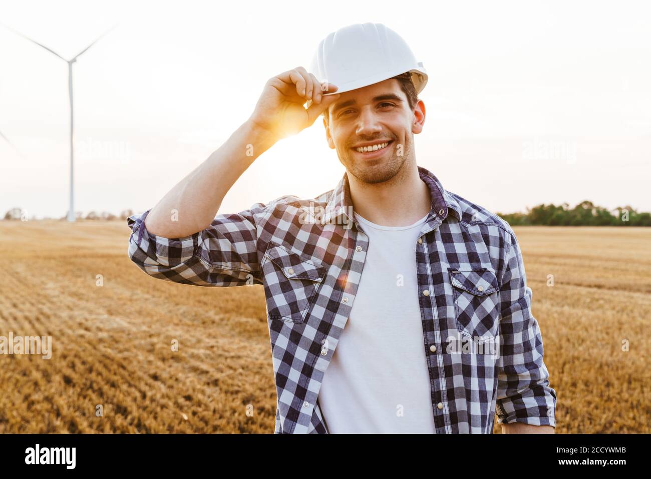 A smiling male engineer using mobile phone while standing at the ...
