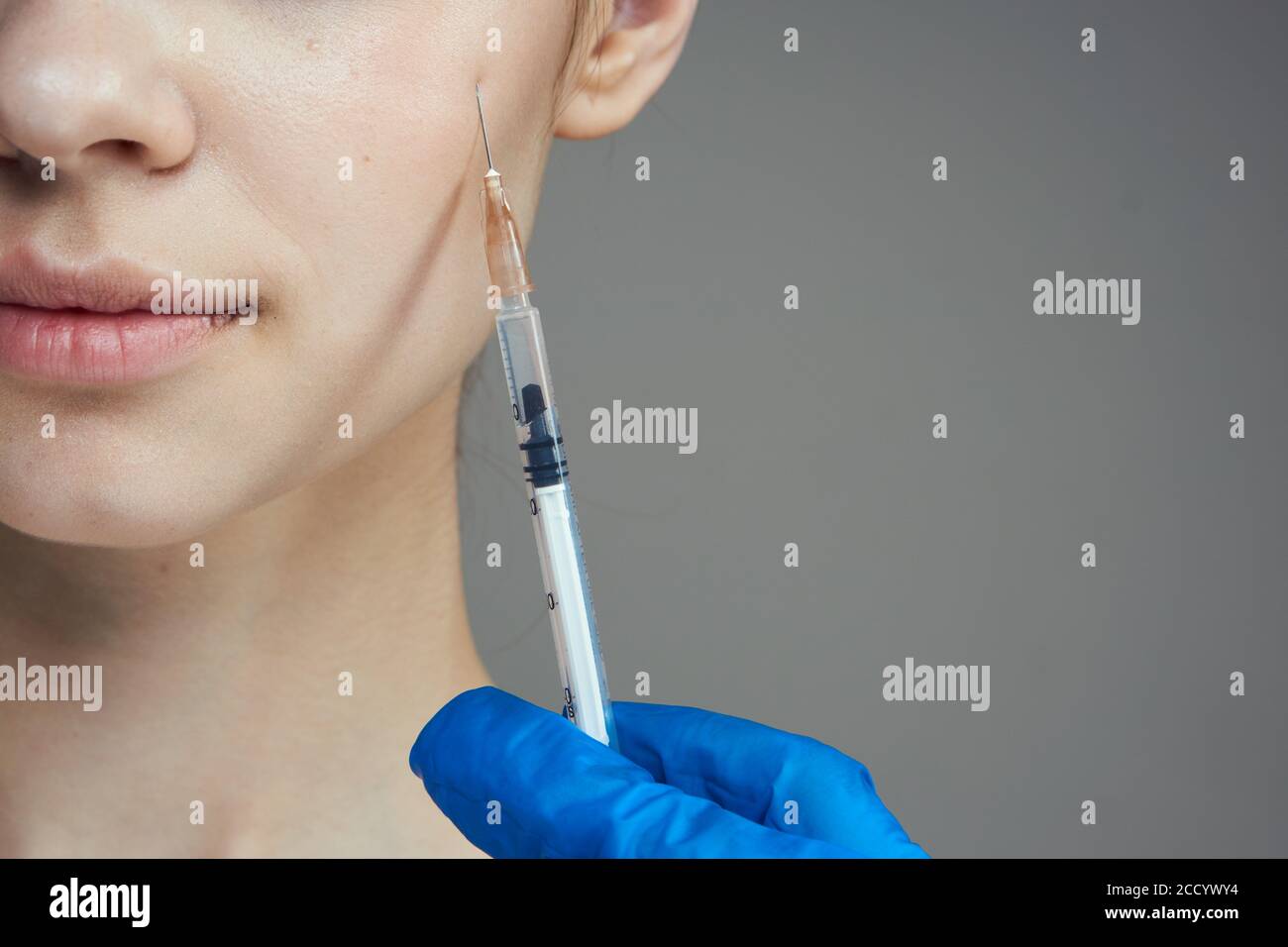 Woman in blue gloves with syringe in hand with botox injection ...