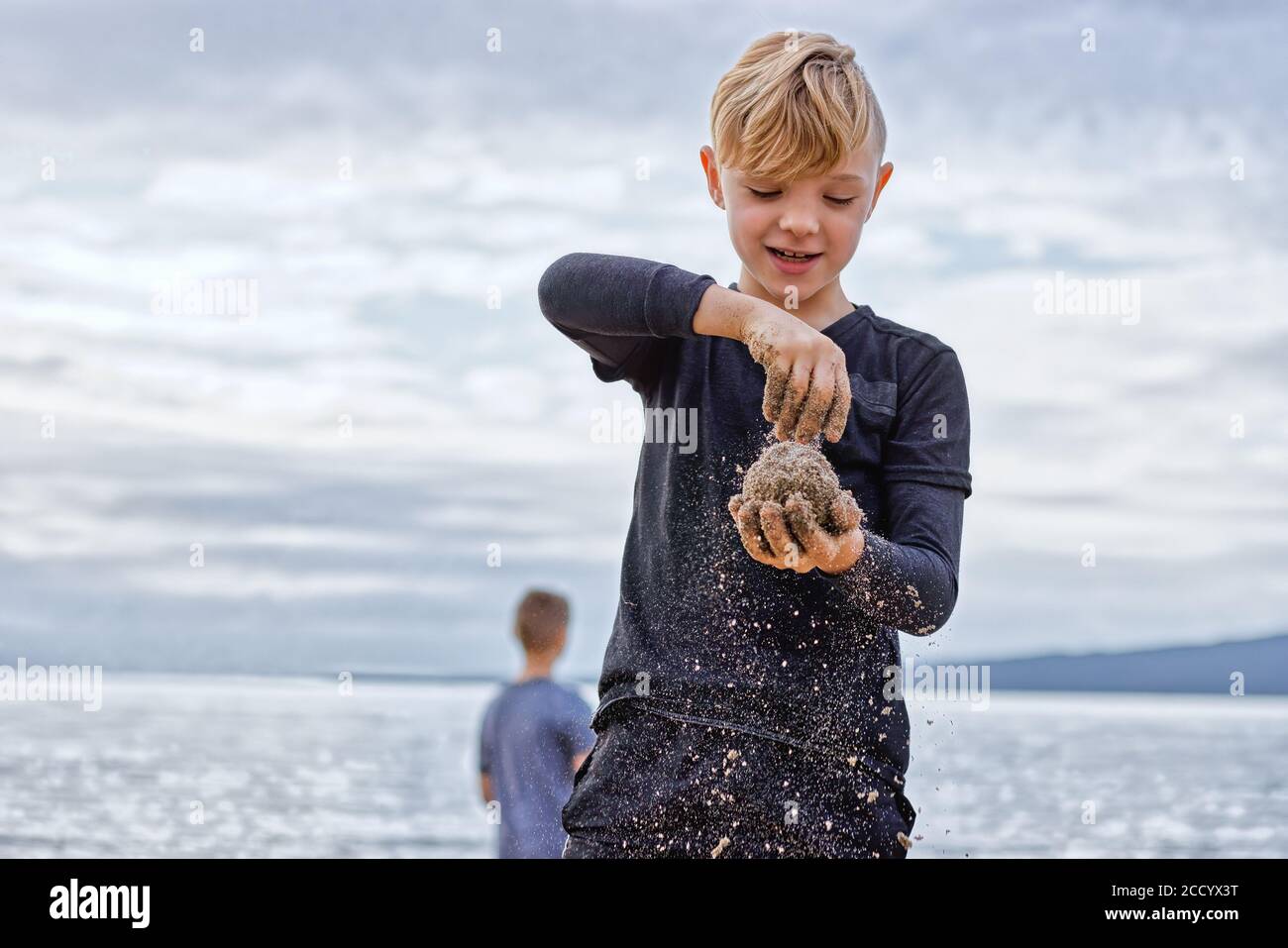 A closeup of a beautiful young boy on the beach, he is slowly letting ...