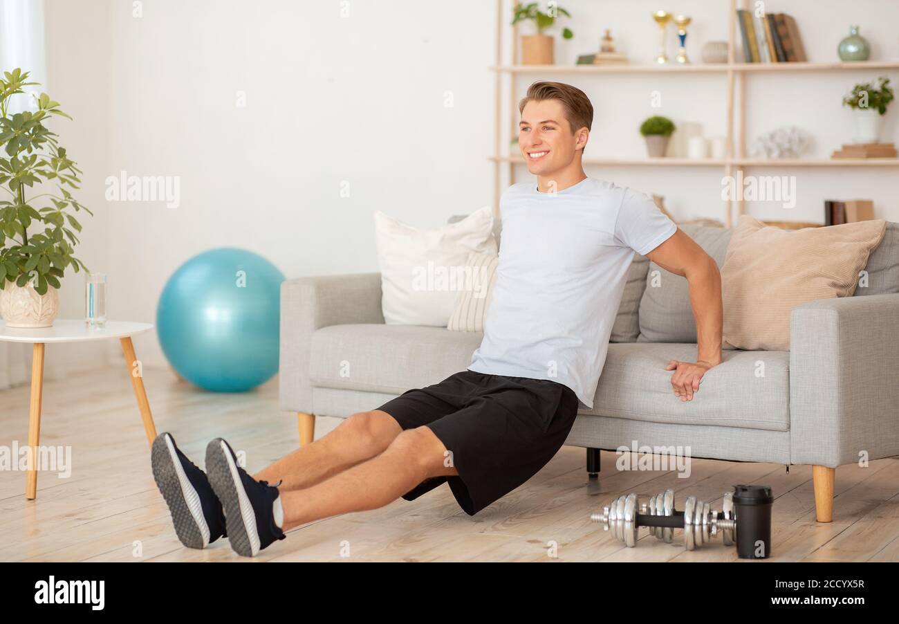 Hard work of athlete at home to keep fit. Guy leans on sofa and does ...