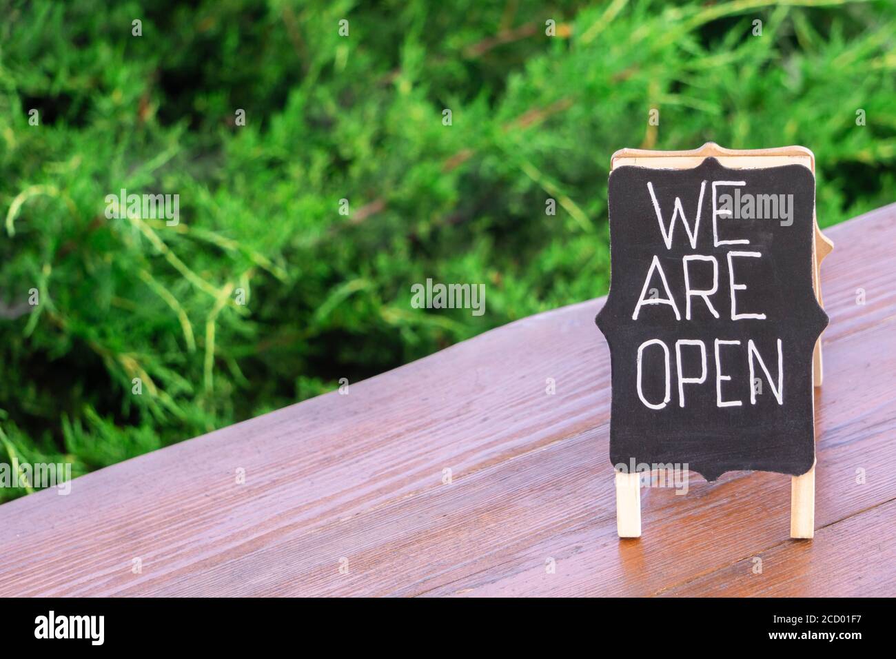 Handwritten text We are Open on blackboard closeup on cafe wooden table ...