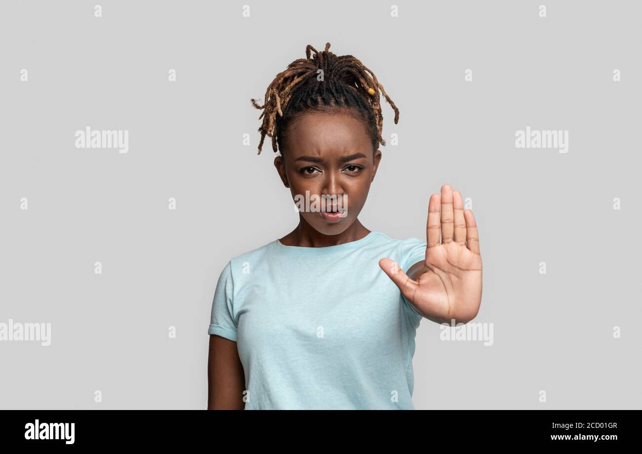 Angry african girl showing stop gesture over grey background Stock ...