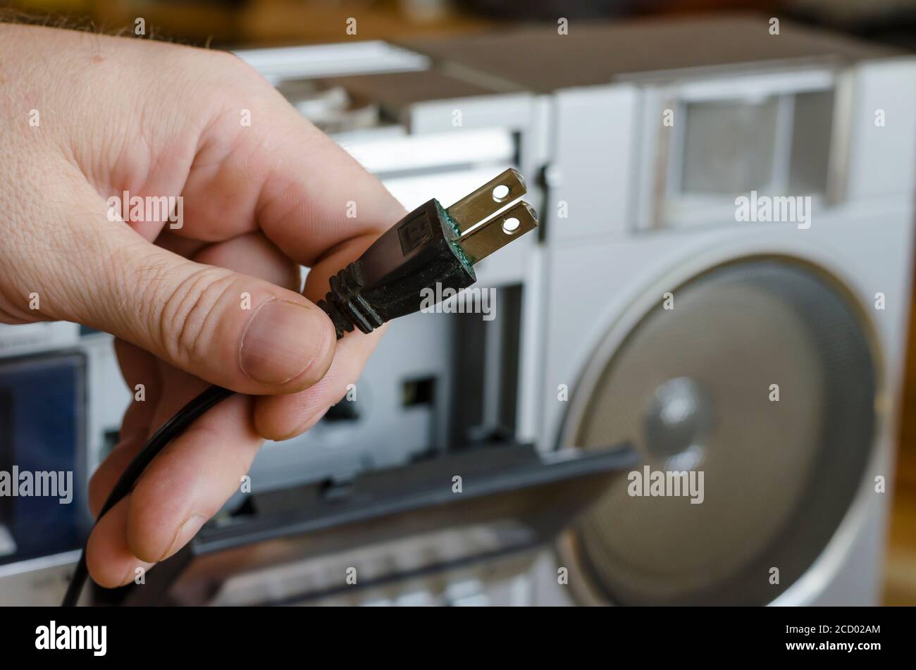 An adult caucasian male hand holds an electric plug of a retro stereo ...