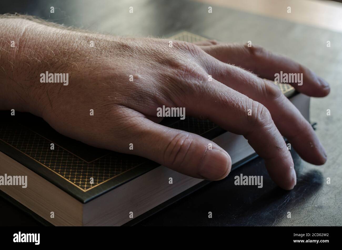 Mature male hand rests on top of a closed book. Green hardcover book ...