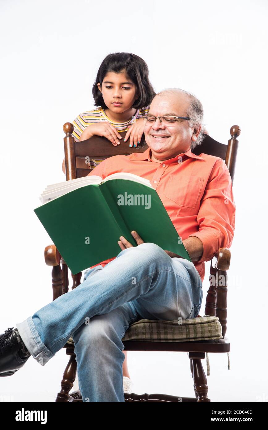 Indian Senior man or grandpa reading book with granddaughter or grand ...
