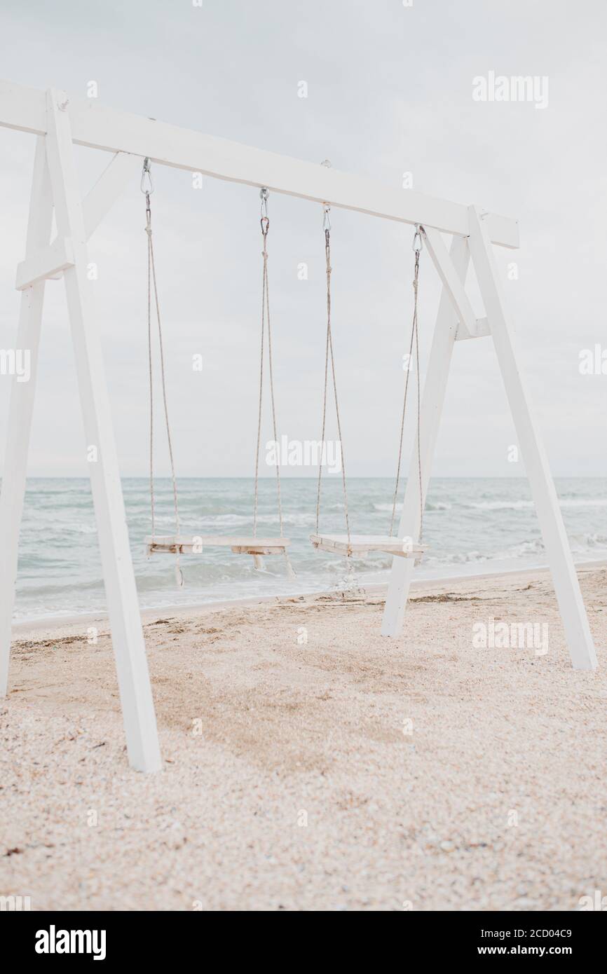 Peaceful scene of a calm sea at sunrise, pastel colors. White swing on ...