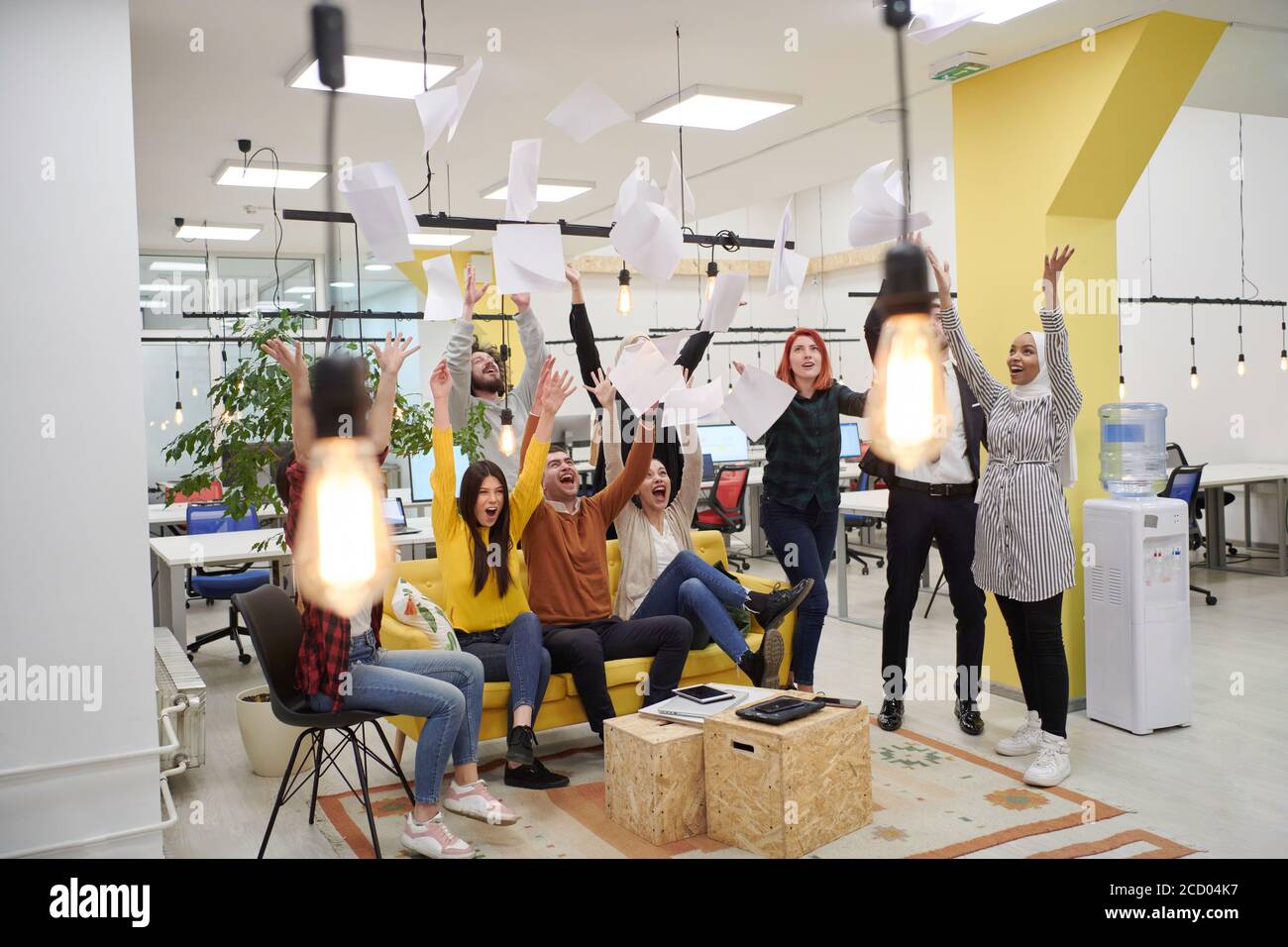 Group of business people throwing paper in air at modern startup office ...