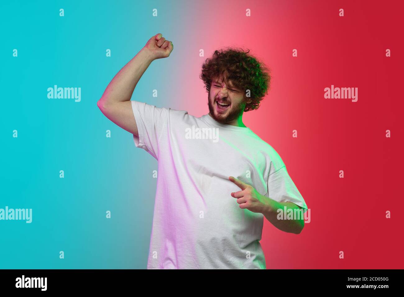Pointing, showing. Caucasian young man's portrait on gradient studio ...