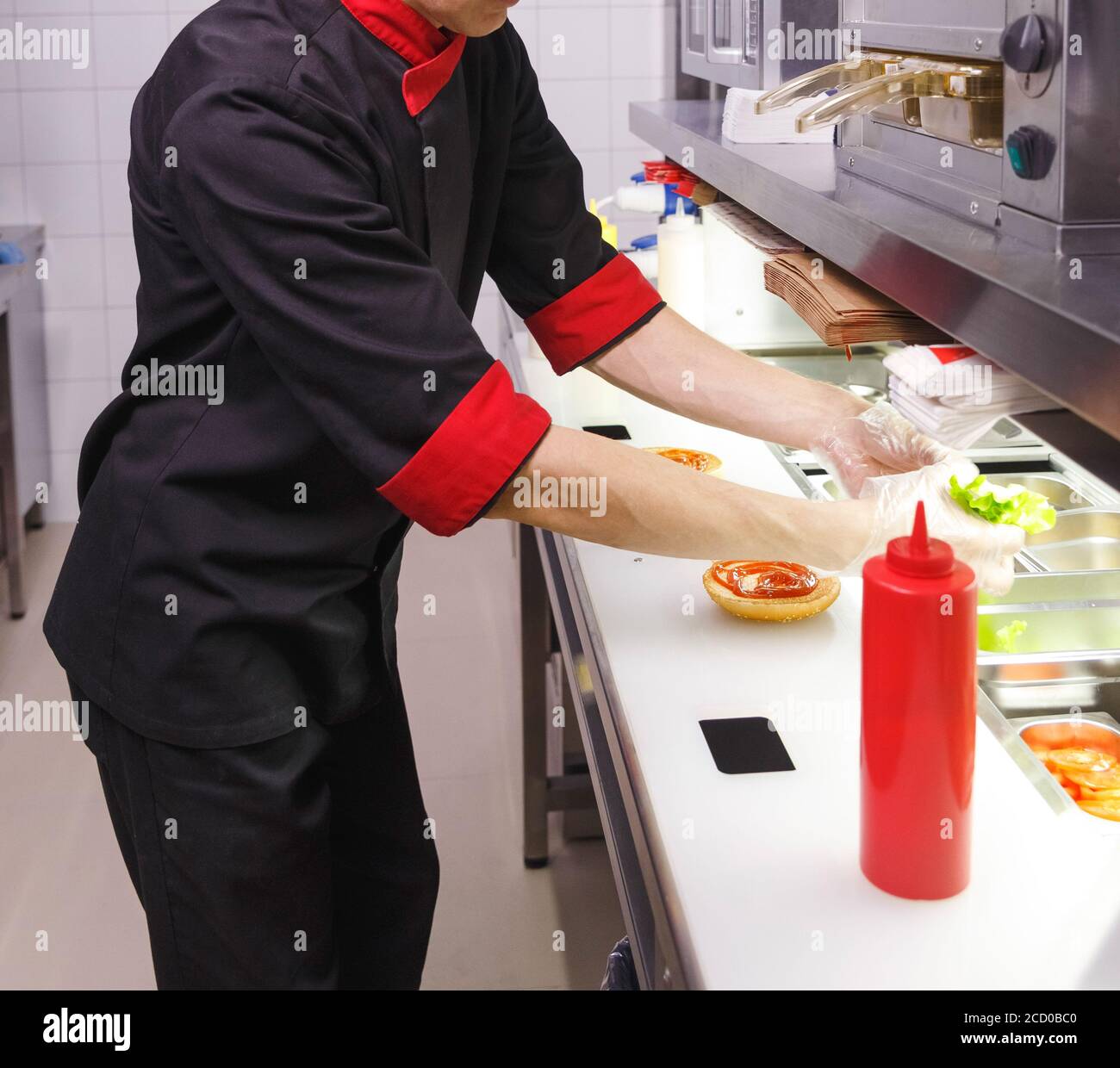 Cook adding lettuce on burger. Preparing burger in restaurant Stock ...
