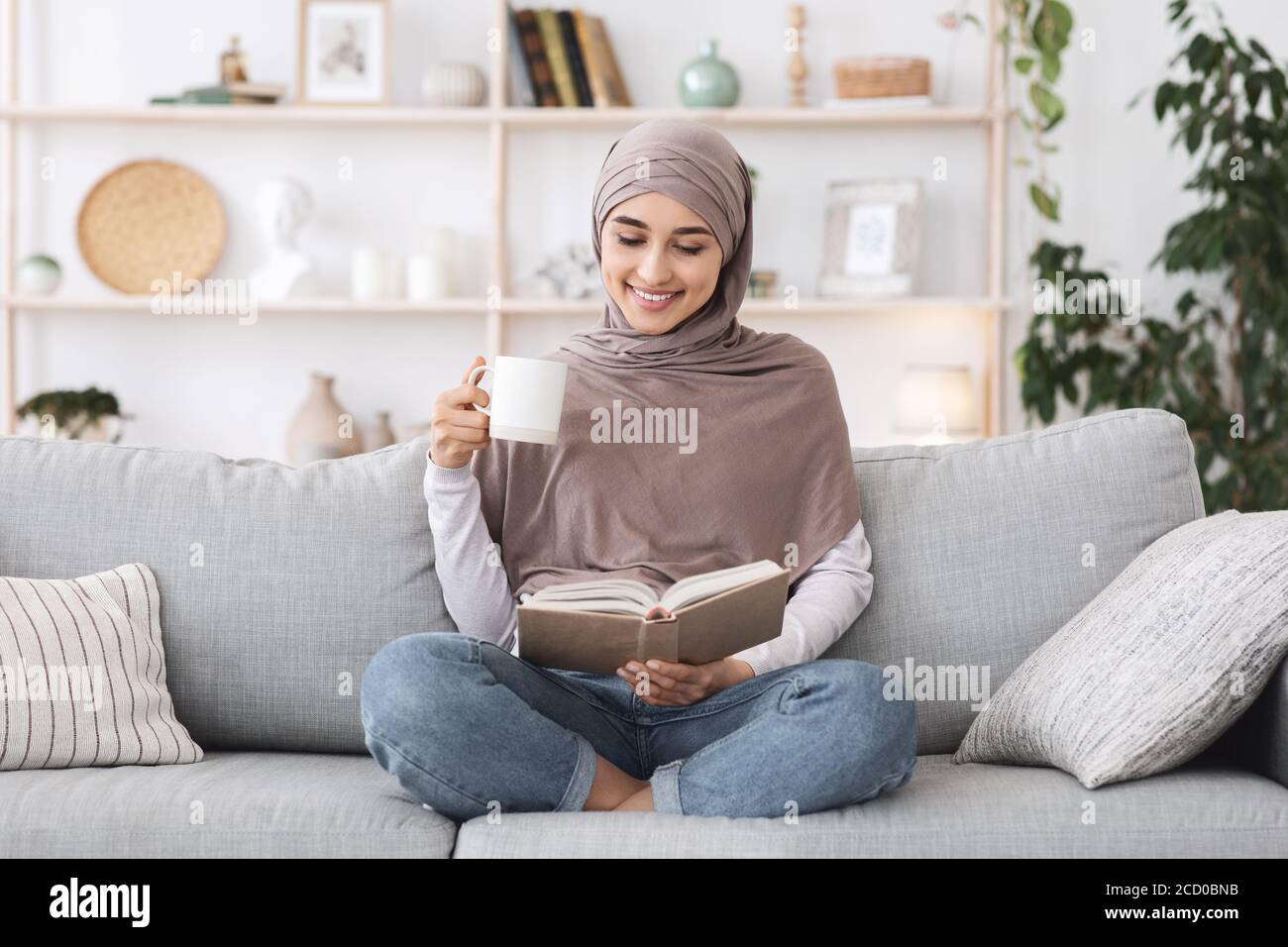 Favorite Leisure. Relaxed Muslim Girl Reading Book And Drinking Tea At ...