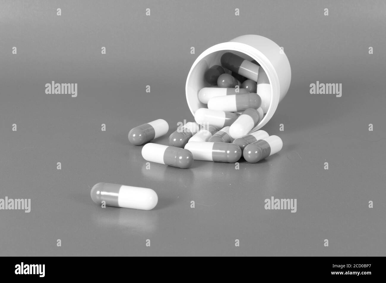 Closeup grayscale shot of medical capsules dropped out from the ...