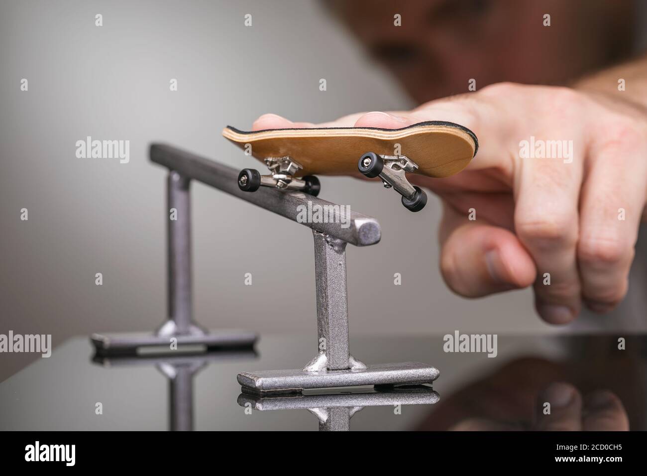 Man rolls a fingerboard on a gray metal railing Stock Photo - Alamy