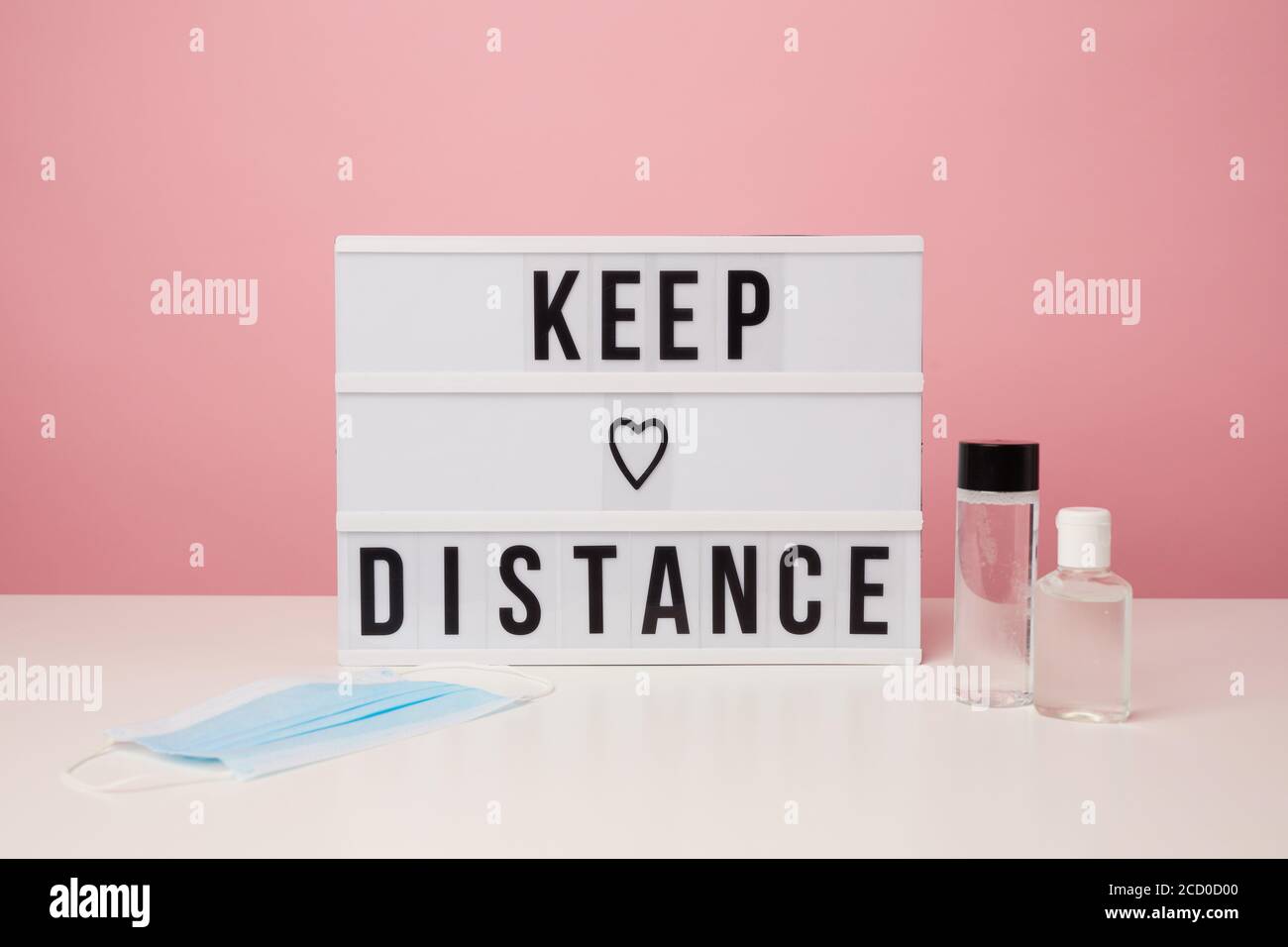 Minimal image of Keep Distance sign and hand sanitizer against pink ...