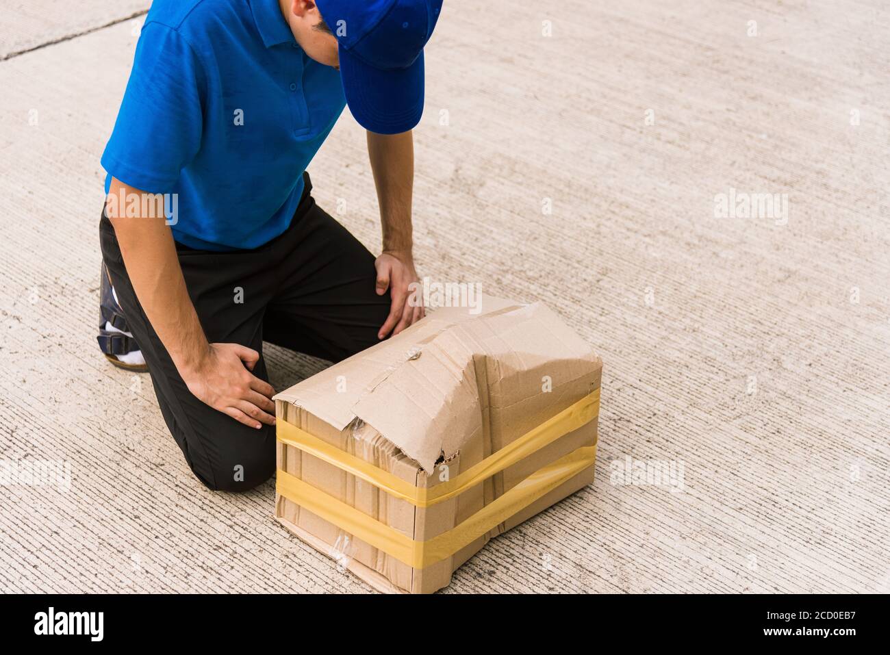 Asian young delivery man in blue uniform he emotional falling courier ...