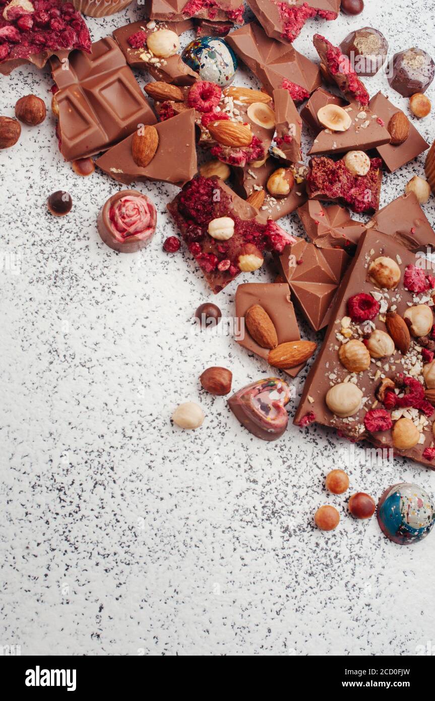 Broken bars of milk chocolate with nuts and sublimated berries and ...