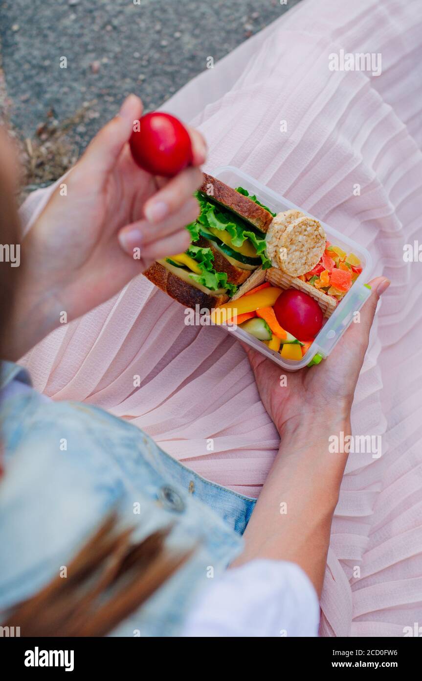 Healthy food concept: Young woman eating from lunch box filled with ...