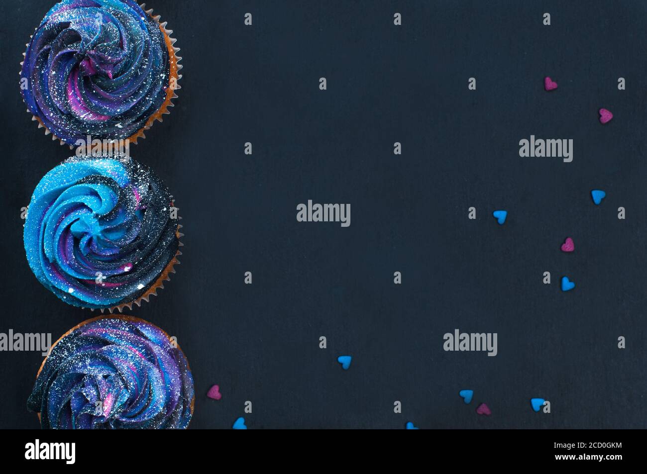 Vanilla cupcakes with galaxy dark whipped cream on black background ...