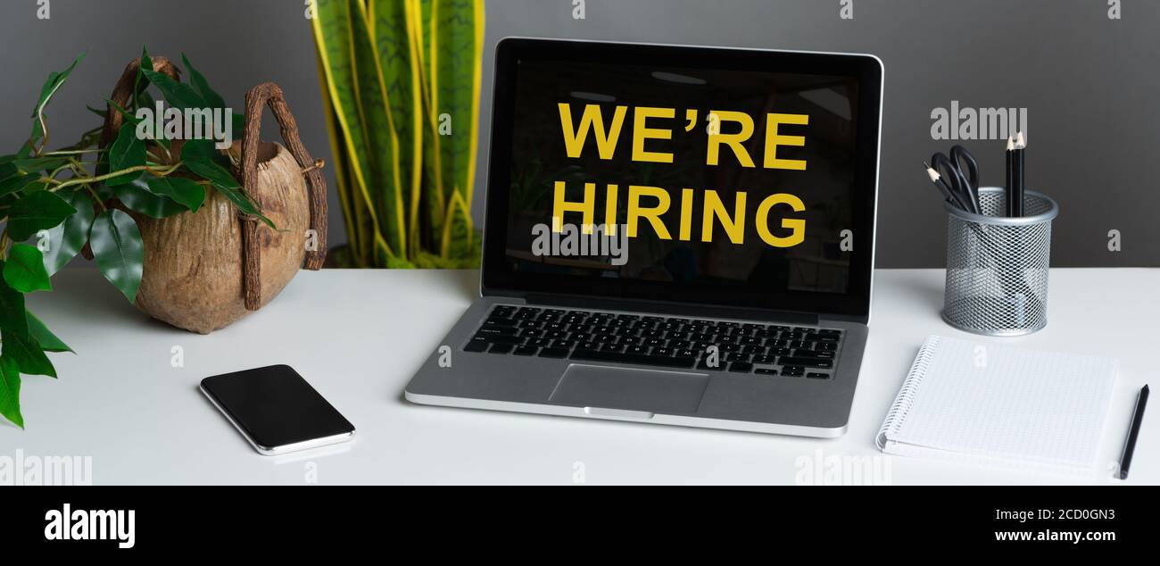 Laptop computer with words WE'RE HIRING on screen at office desk ...