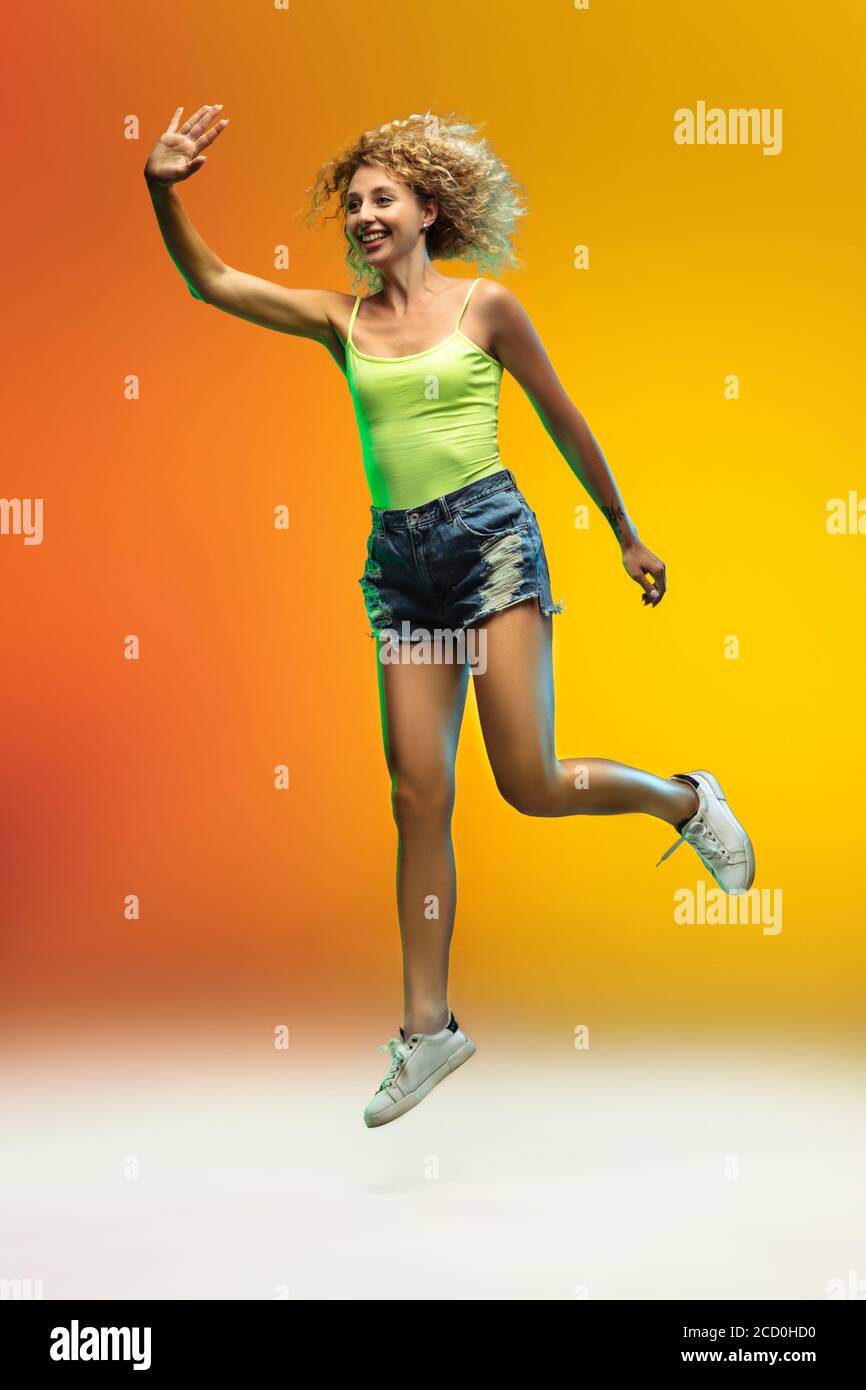 Greeting. Jumping caucasian young woman's portrait on gradient studio ...