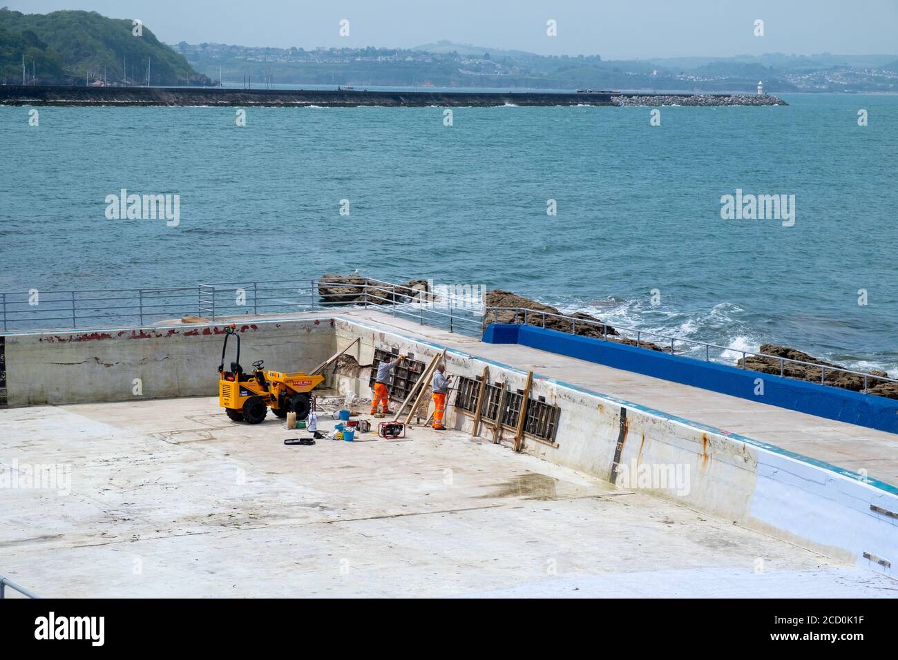 Workers repairing an outdoor swimming pool (Shoalstone Pool) at Brixham ...