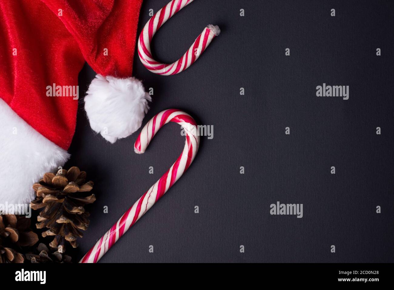 red santa claus hat on a black background, next to christmas candy in ...