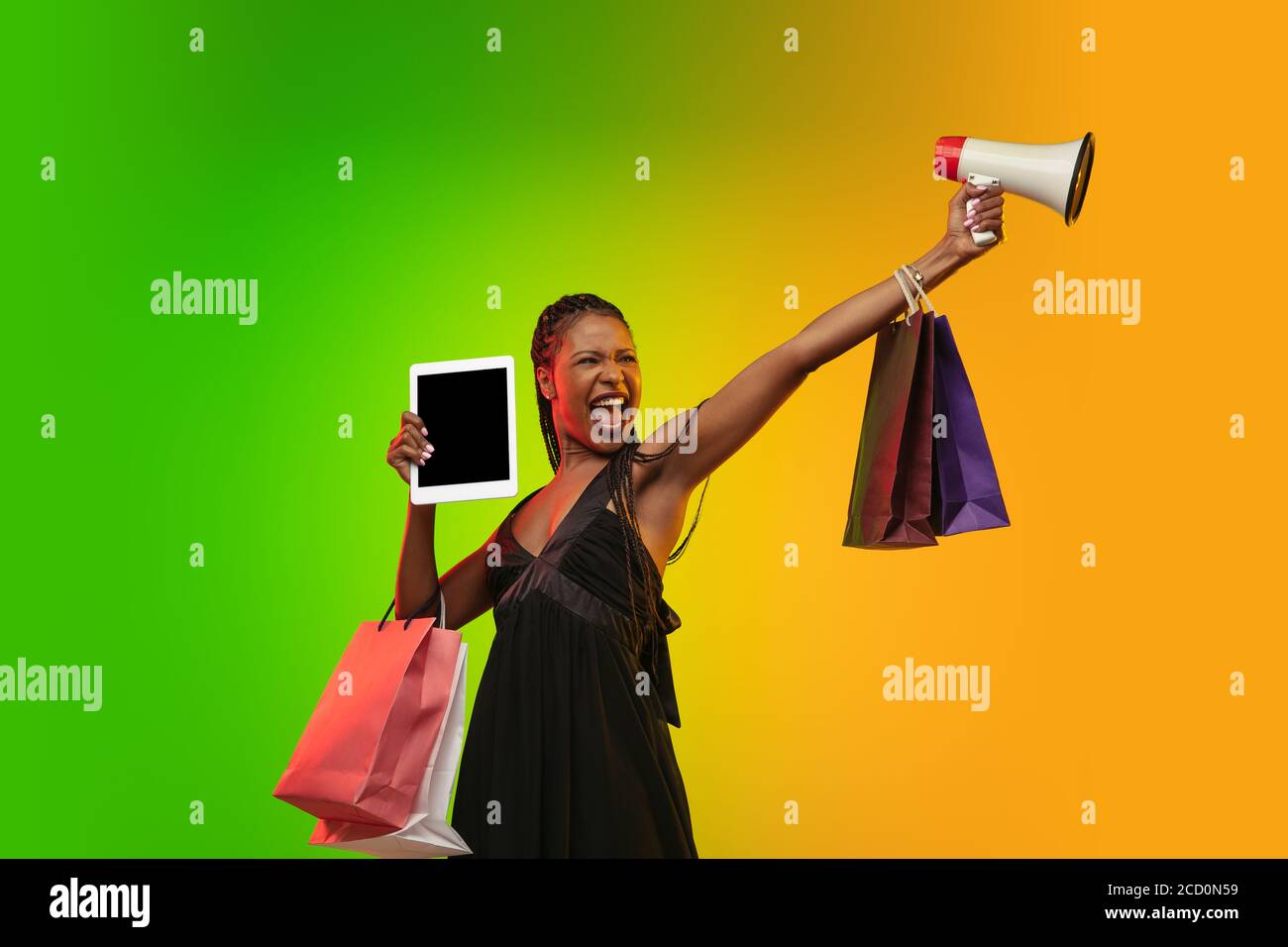 Shouting with shopping bags and tablet. Portrait of young woman in neon ...