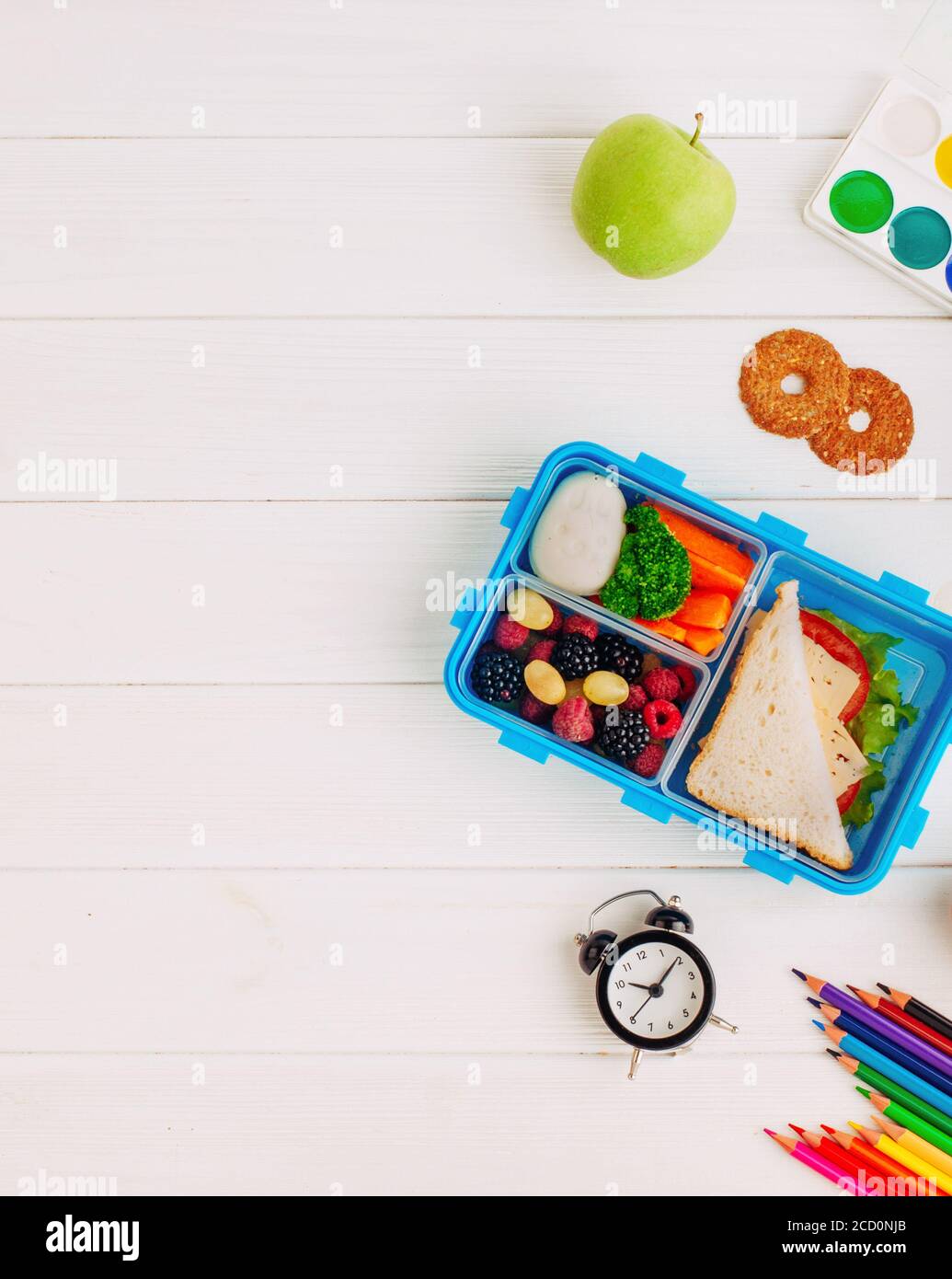 Open lunch box with sandwich, vegetables, egg, fresh berries with clock ...