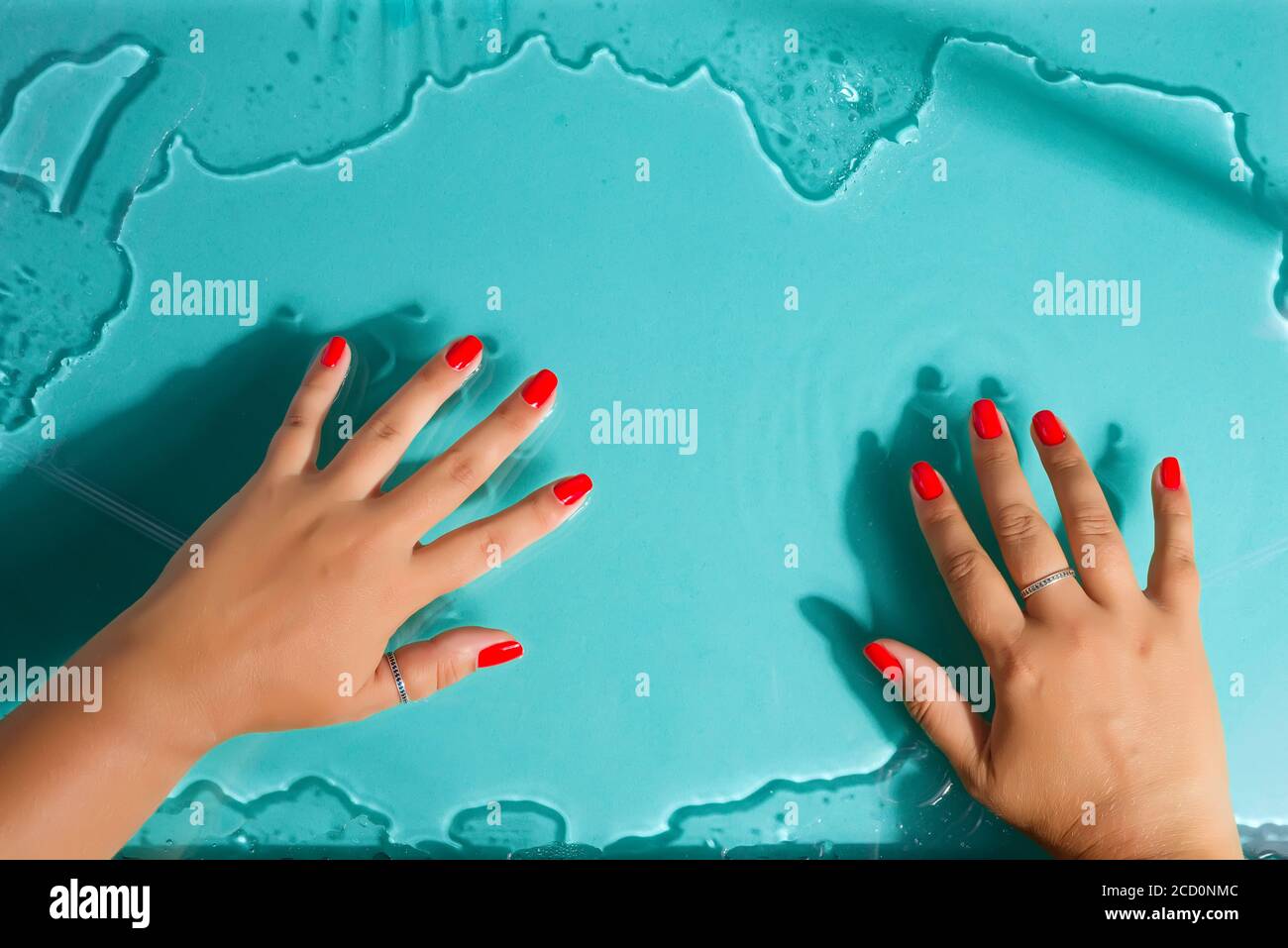 Woman's hand above turquoise background with water under glass texture ...