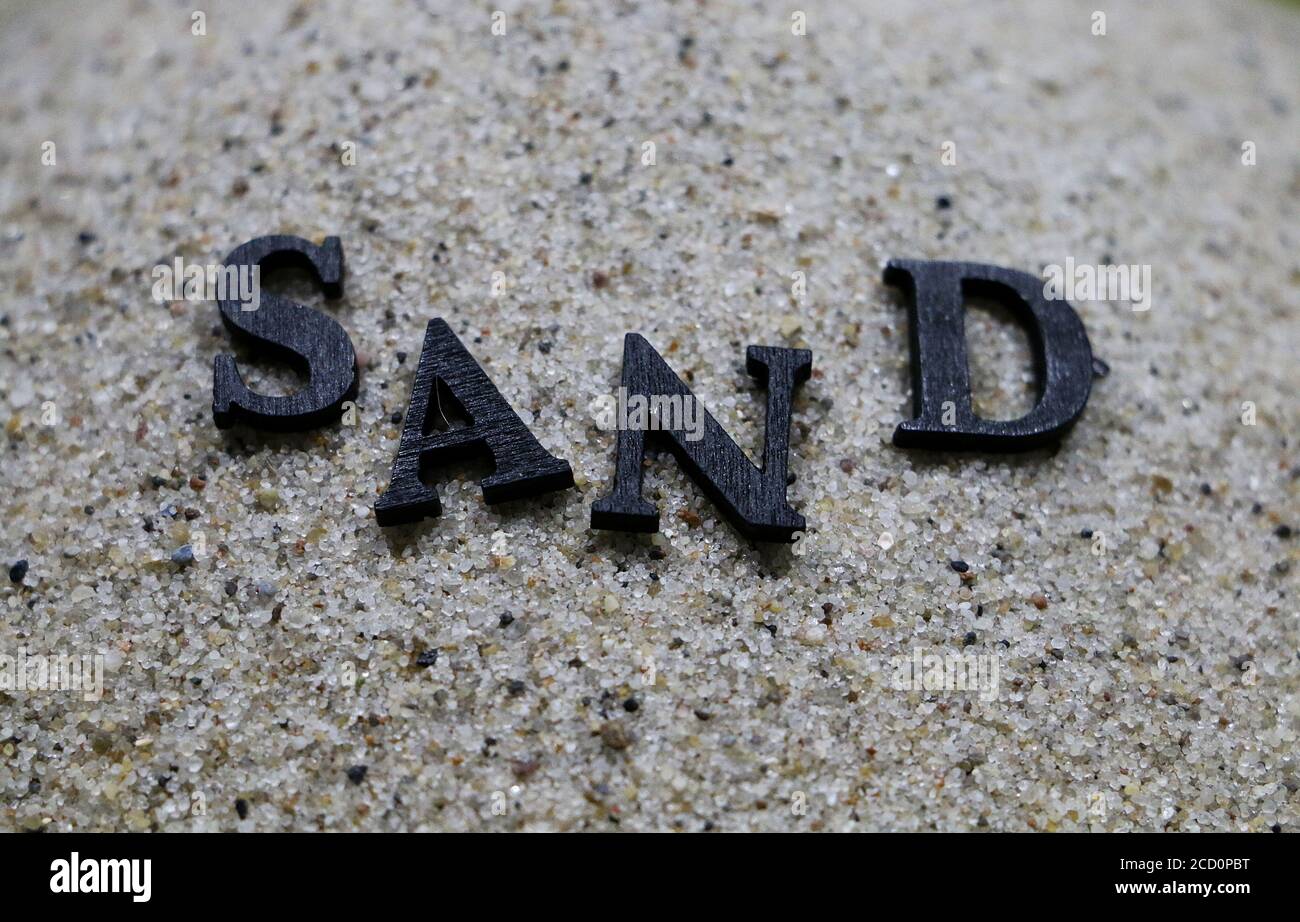 Word SAND made of black letters on the wet sand at the beach Stock ...