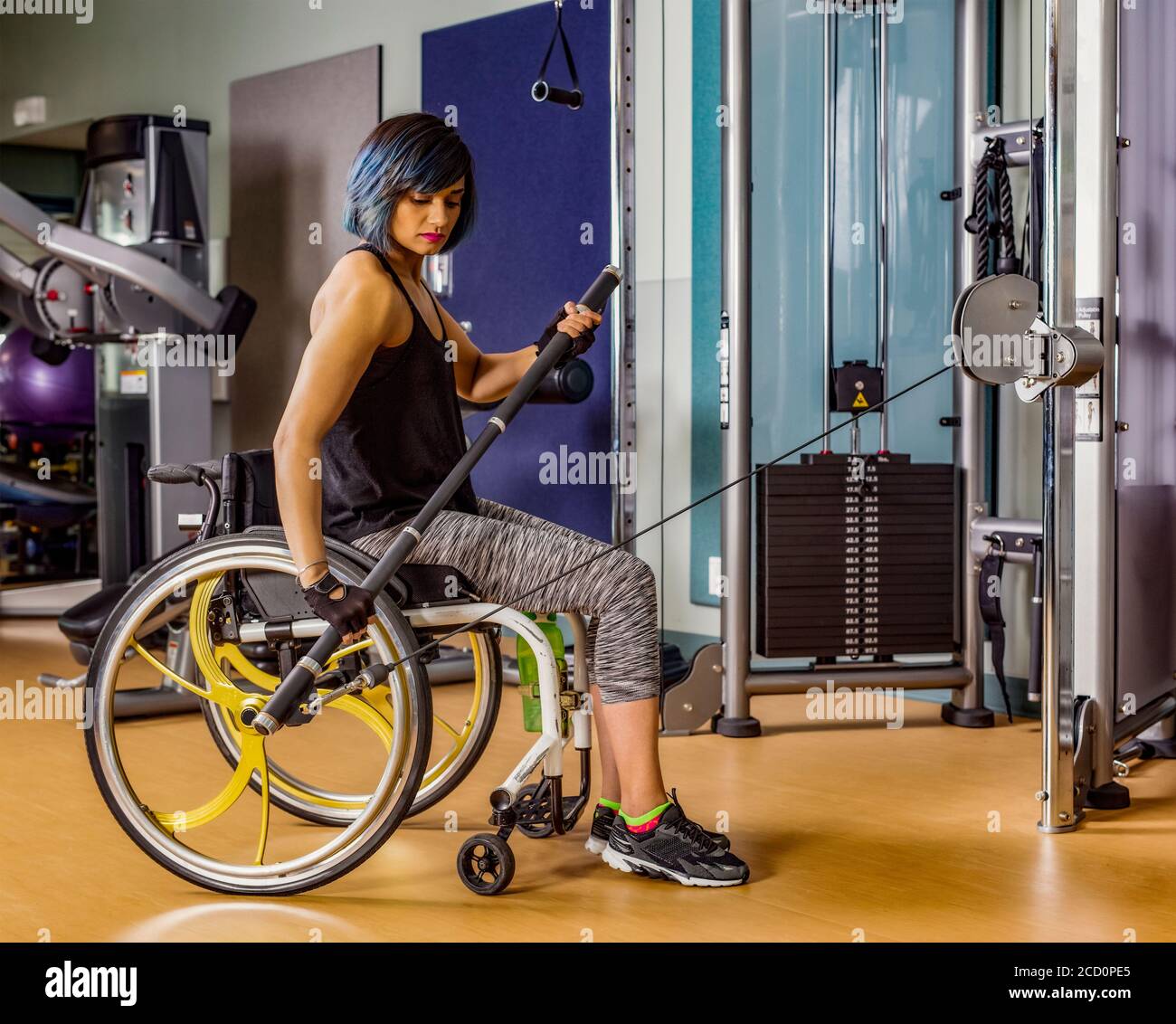 A view from the side of a paraplegic woman working out using a bar ...